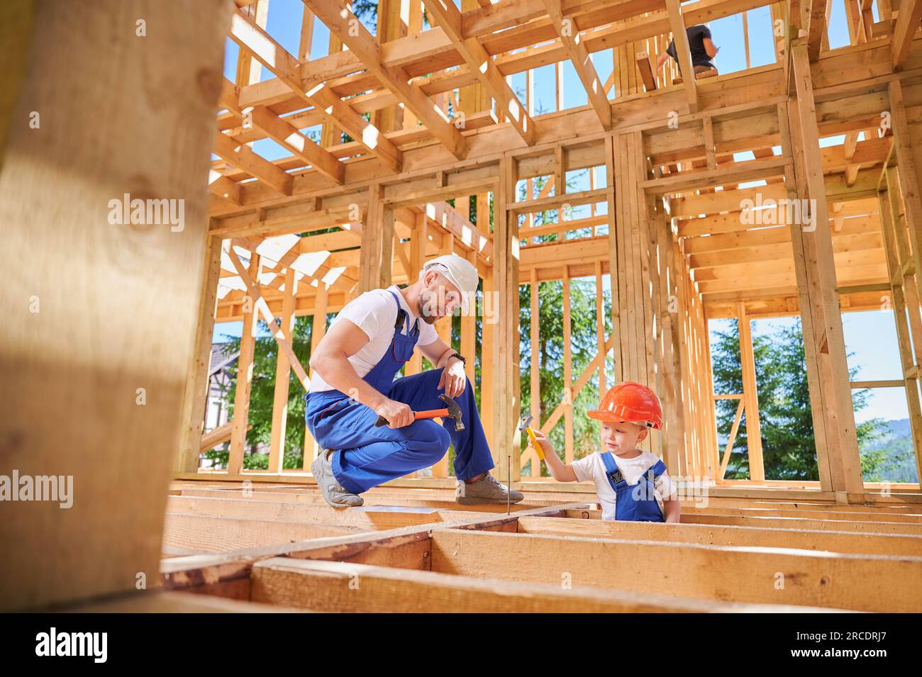 Father with toddler son constructing wooden frame house. Man builder ...