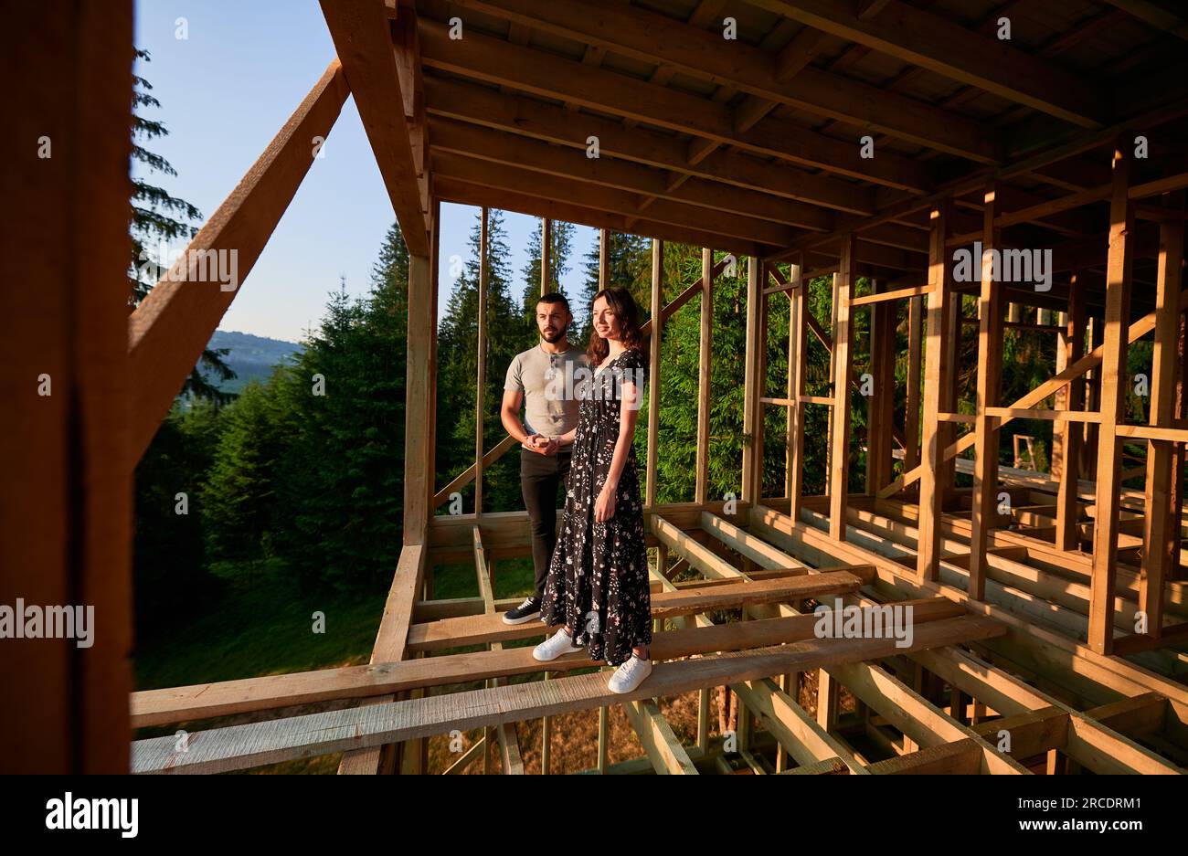 Man and woman inspecting their future wooden frame house nestled in the ...