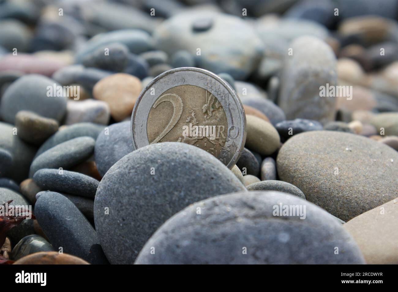 European currency. Used old 2 euro coin. Coin on sunny rocky beach ...