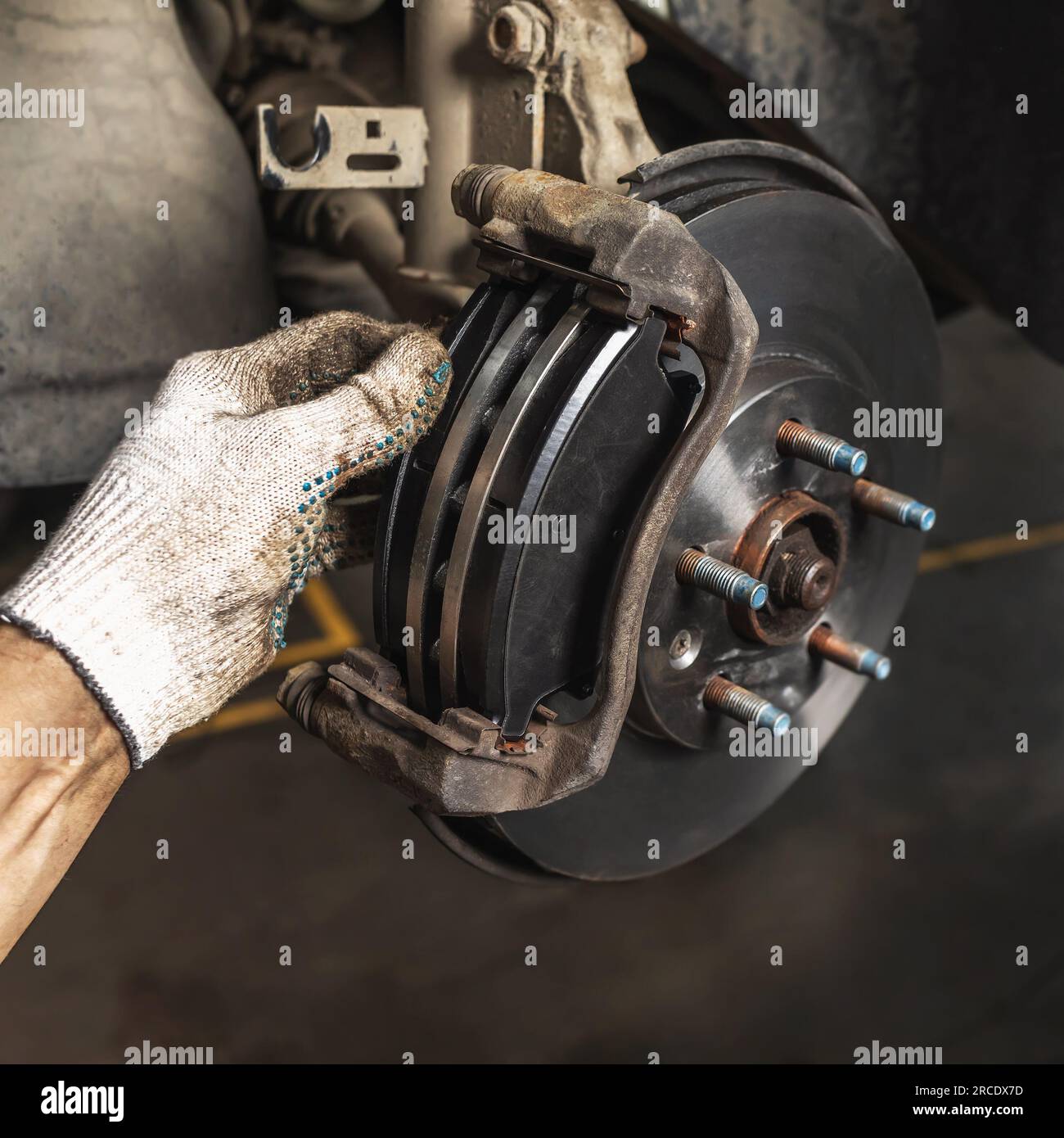 Auto mechanic installed new brake pads on a new brake disc, is engaged ...