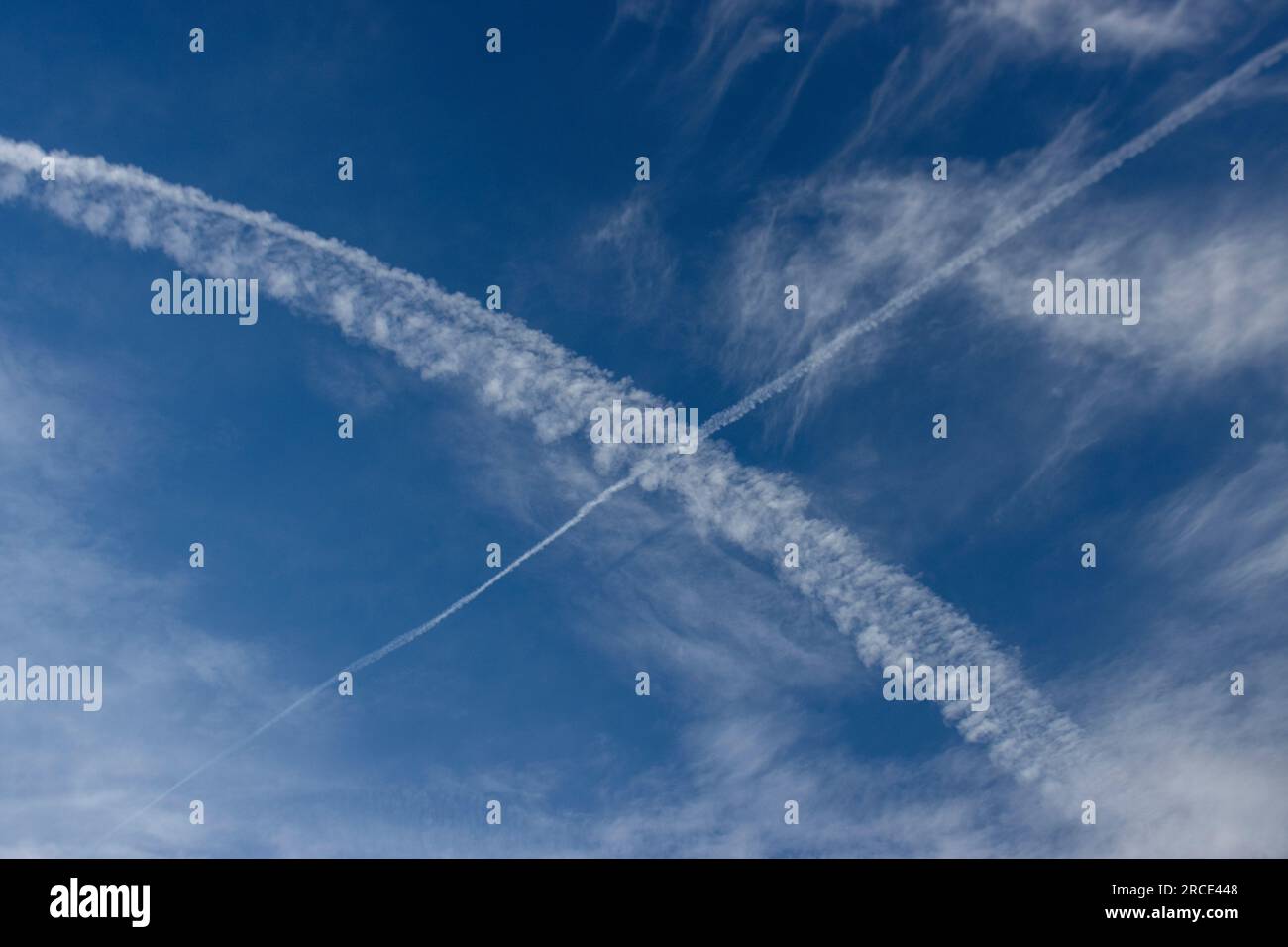 Flight Trails criss crossed in the blue sky with some clouds too Stock ...