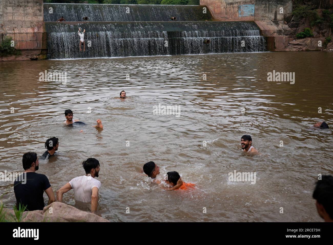 Men cool themselves off in a water overflow as temperatures reached 36 ...