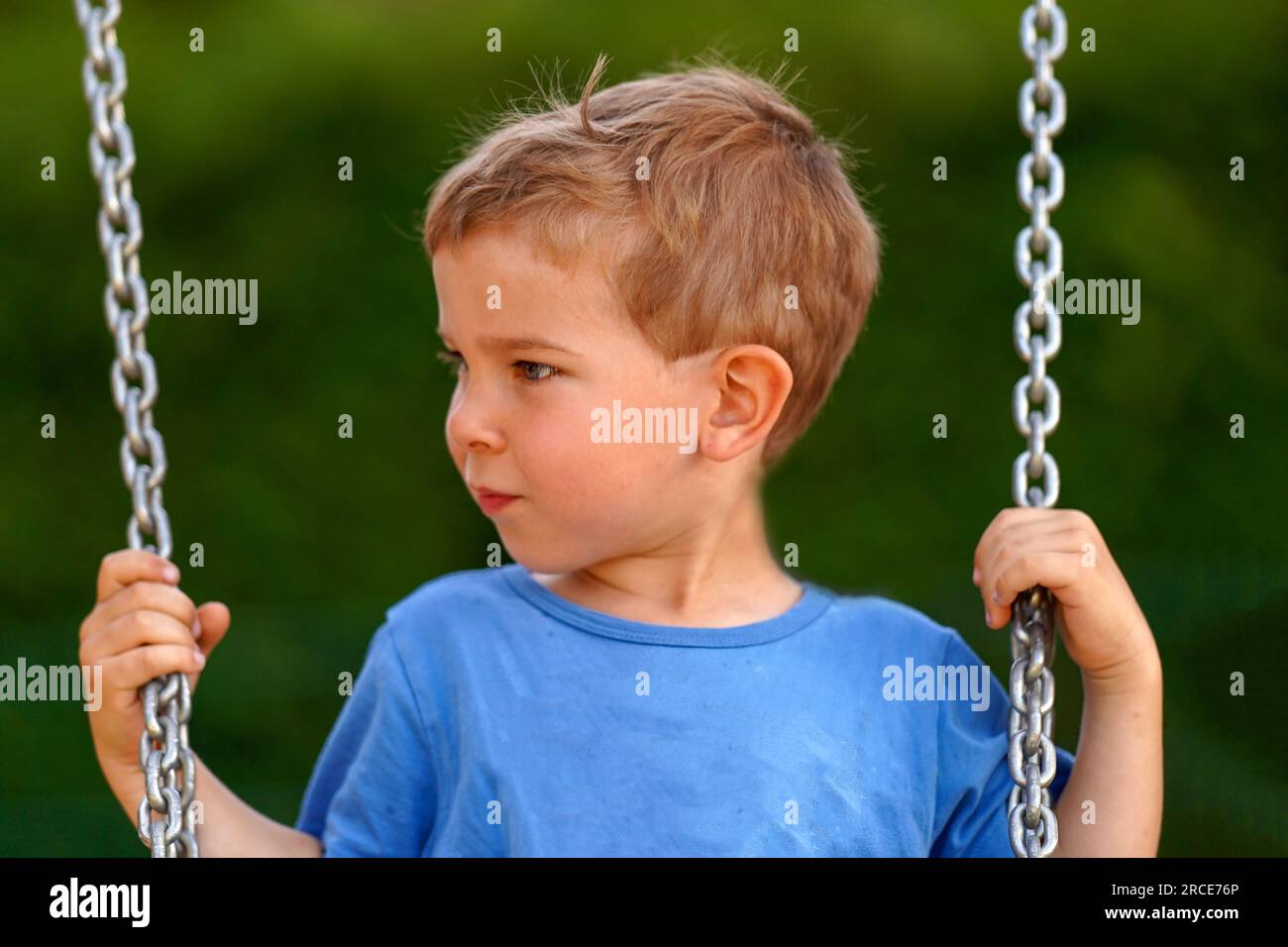 A little boy on a swing. Cute child playing on swing in backyard at ...