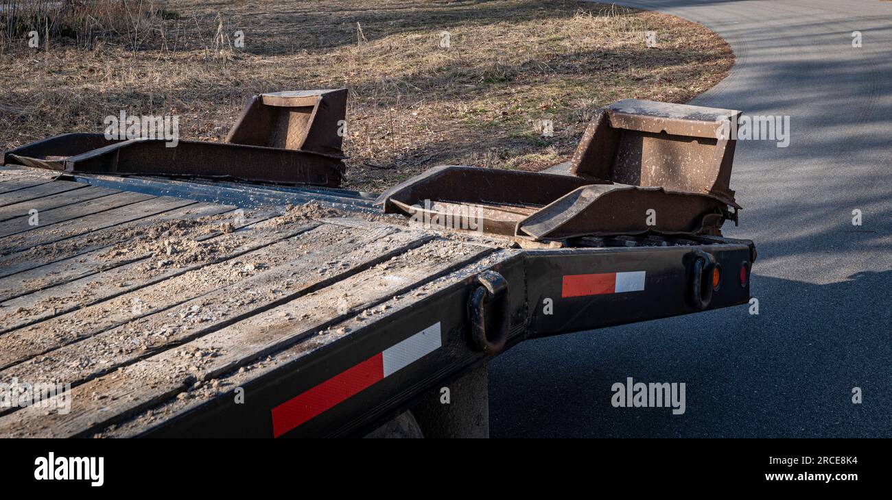 Raised ramps on the back end of an empty flatbed trailer parked on the ...