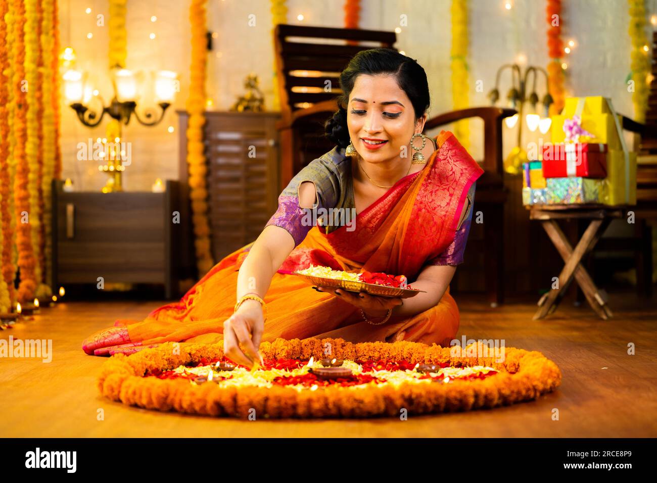 Happy traditional indian girl decorating Rangoli with flowers for ...