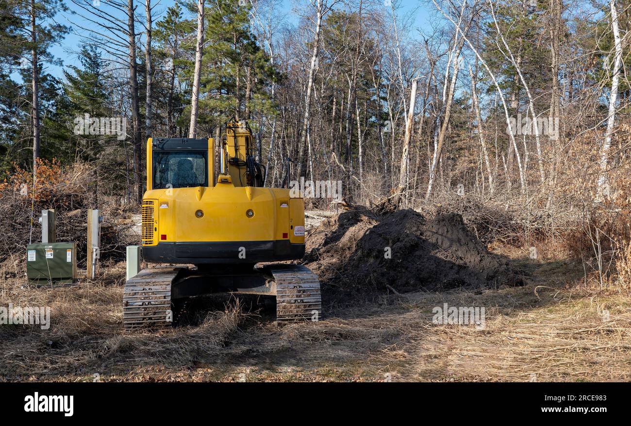 Yellow hydraulic backhoe excavator with tracks is parked near utility ...