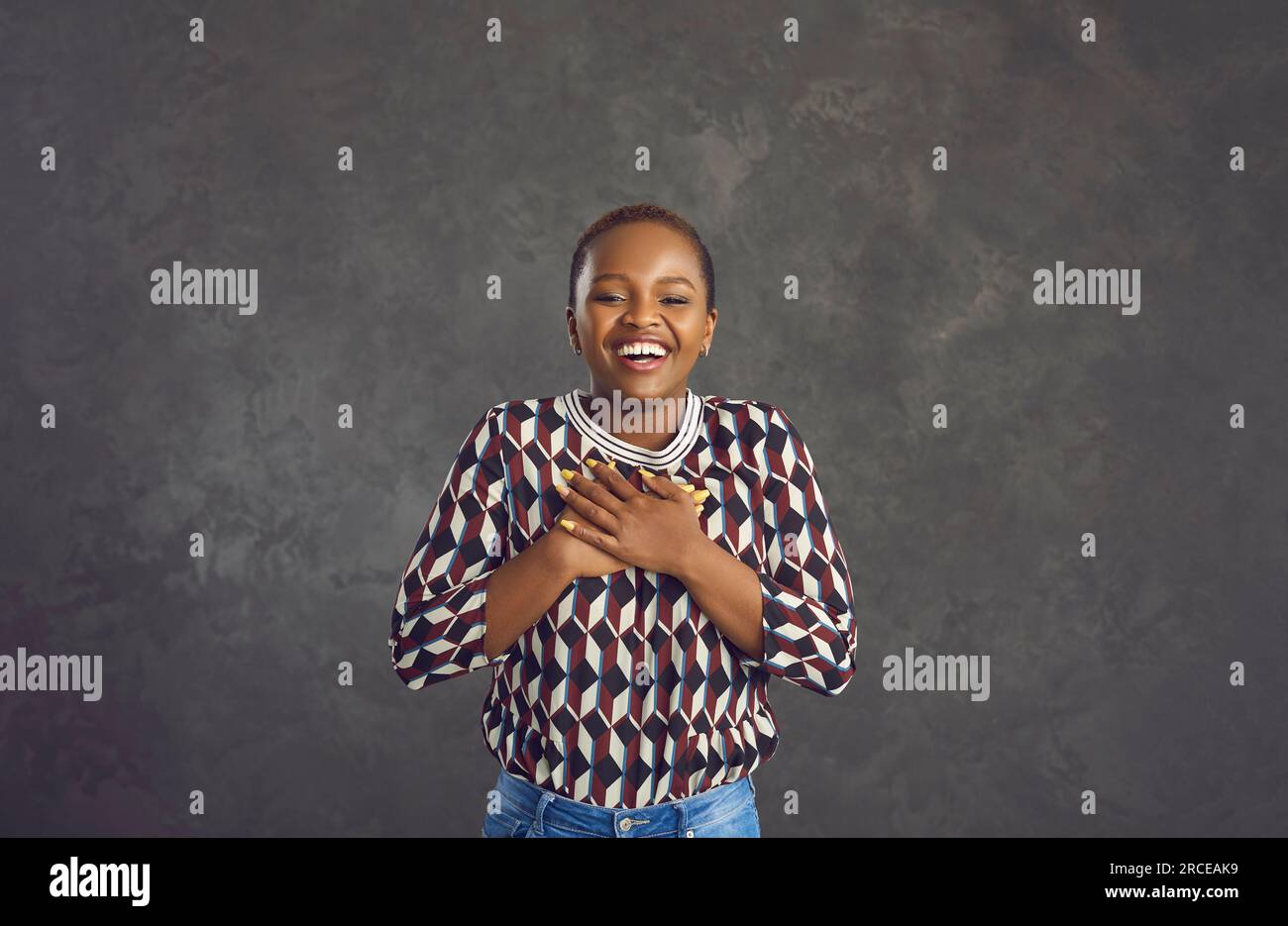 Happy young black woman smiling, holding hands on her chest and saying ...