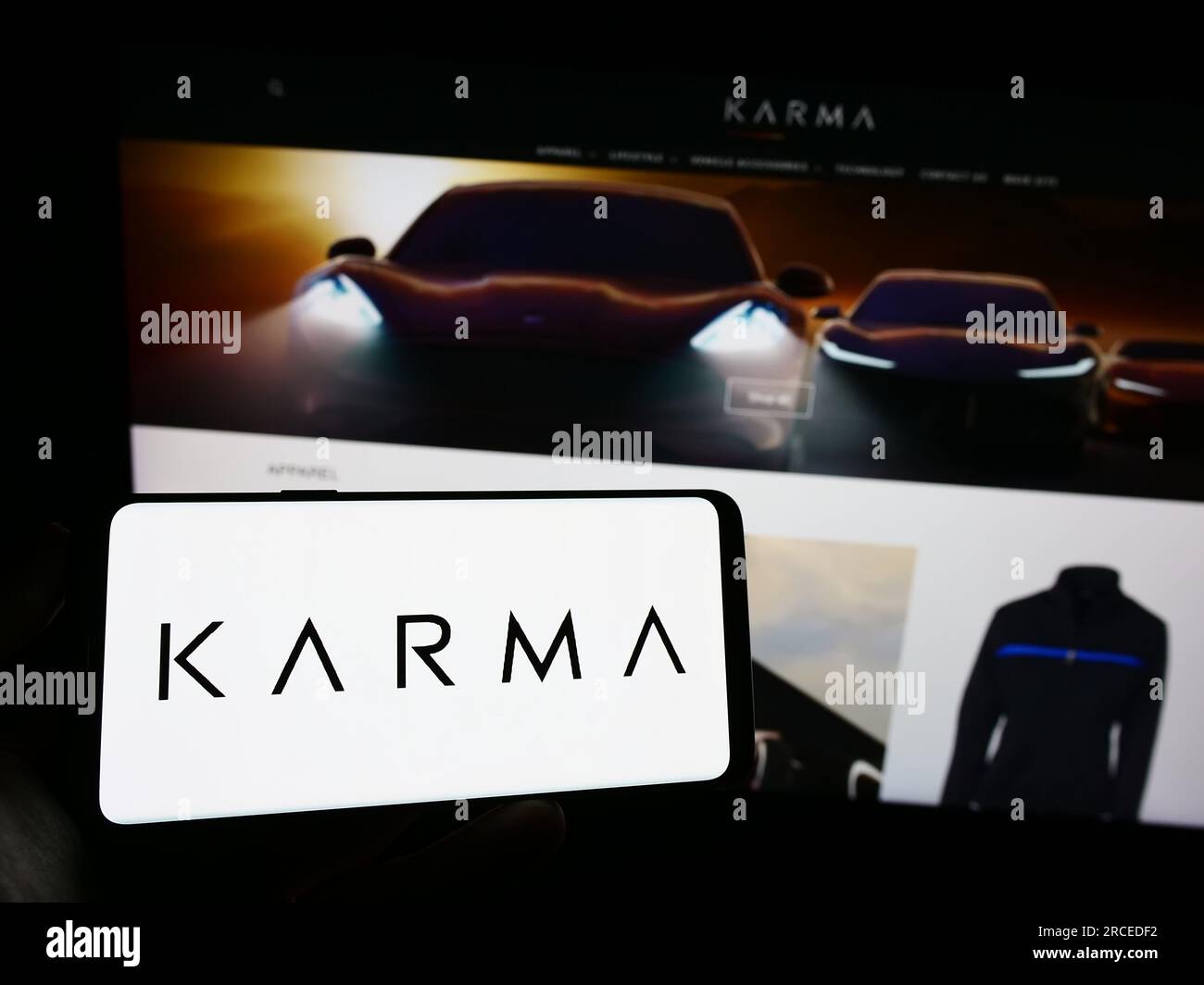Person holding mobile phone with logo of electric vehicle company Karma ...