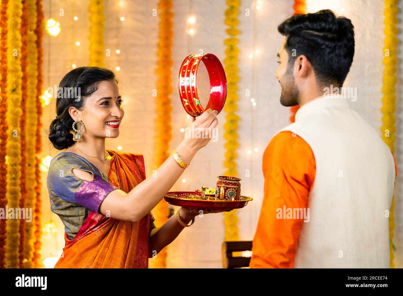 Indian wife looking husband face through sieve during karva Chauth ...