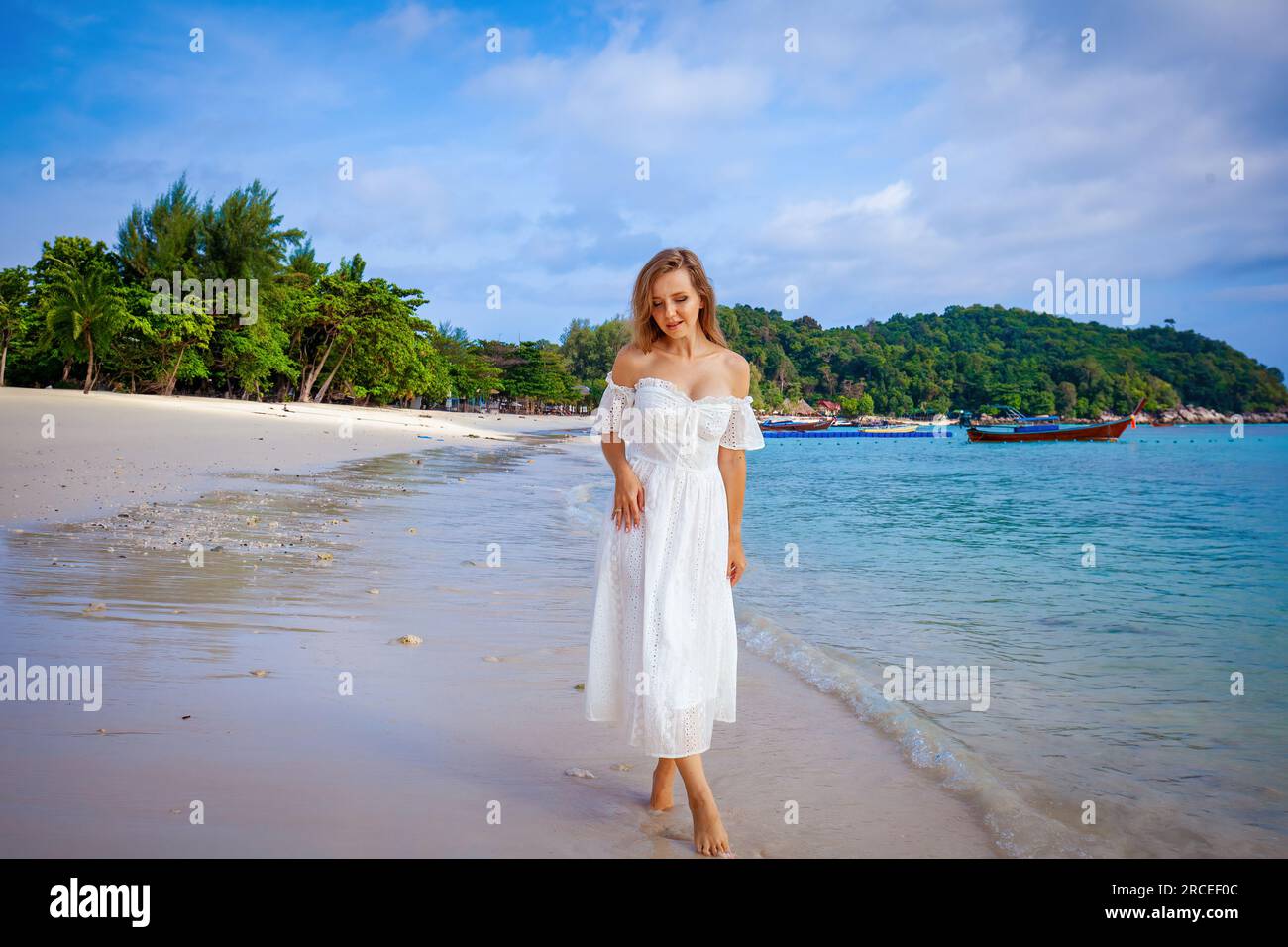 Woman in white dress walks on tropical beach with seashell Stock Photo ...