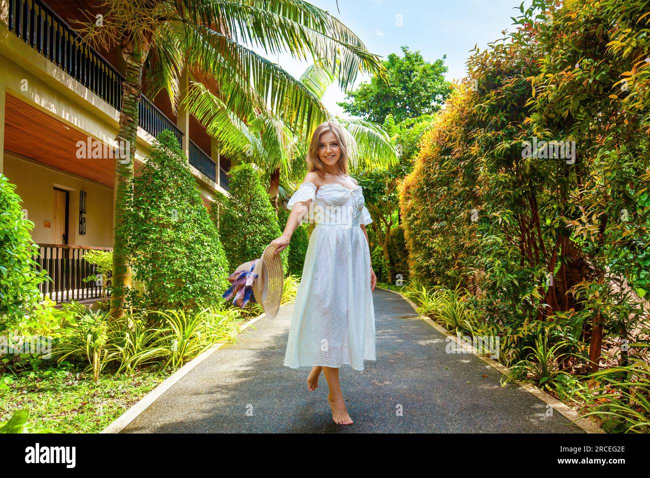 Beautiful woman with flowing hair walking along a path lined with lush ...