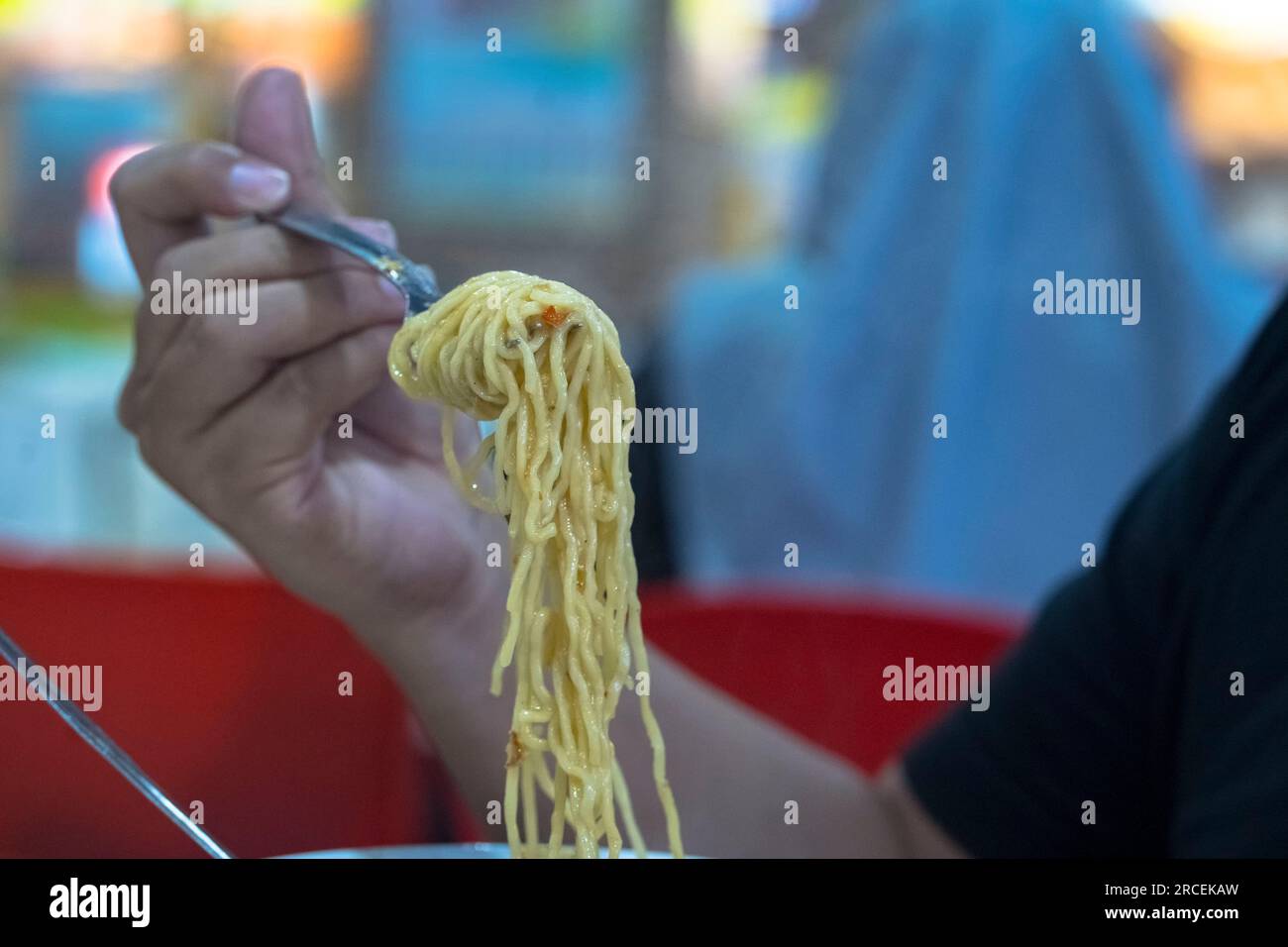 Close up of two hands prepare to eat Mie Ayam or popular Indonesian ...