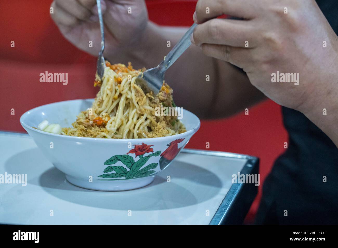 Close up of two hands prepare to eat Mie Ayam or popular Indonesian ...