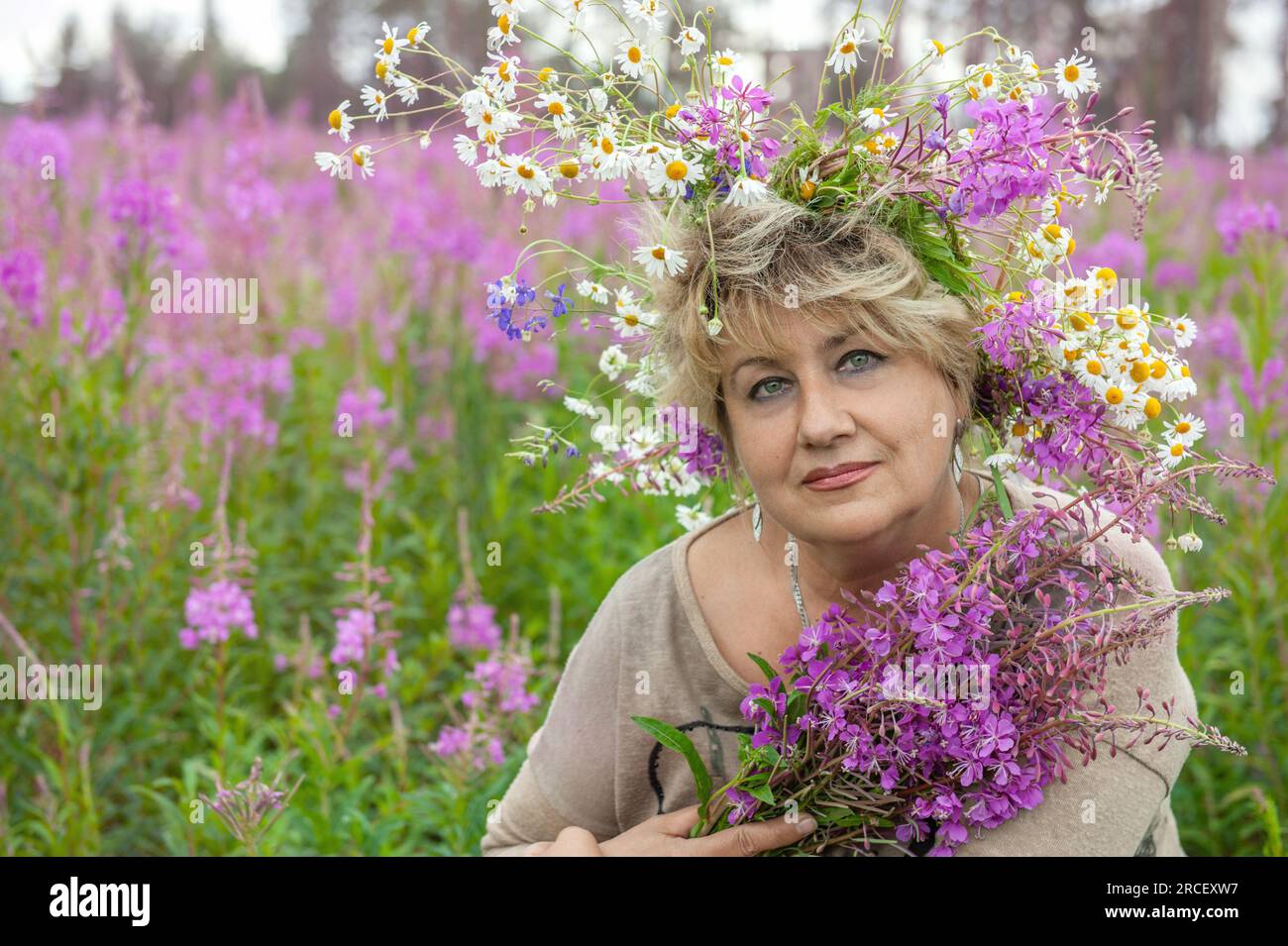 Beautiful 60s mid mature woman at nature in a a wreath of flowers in ...