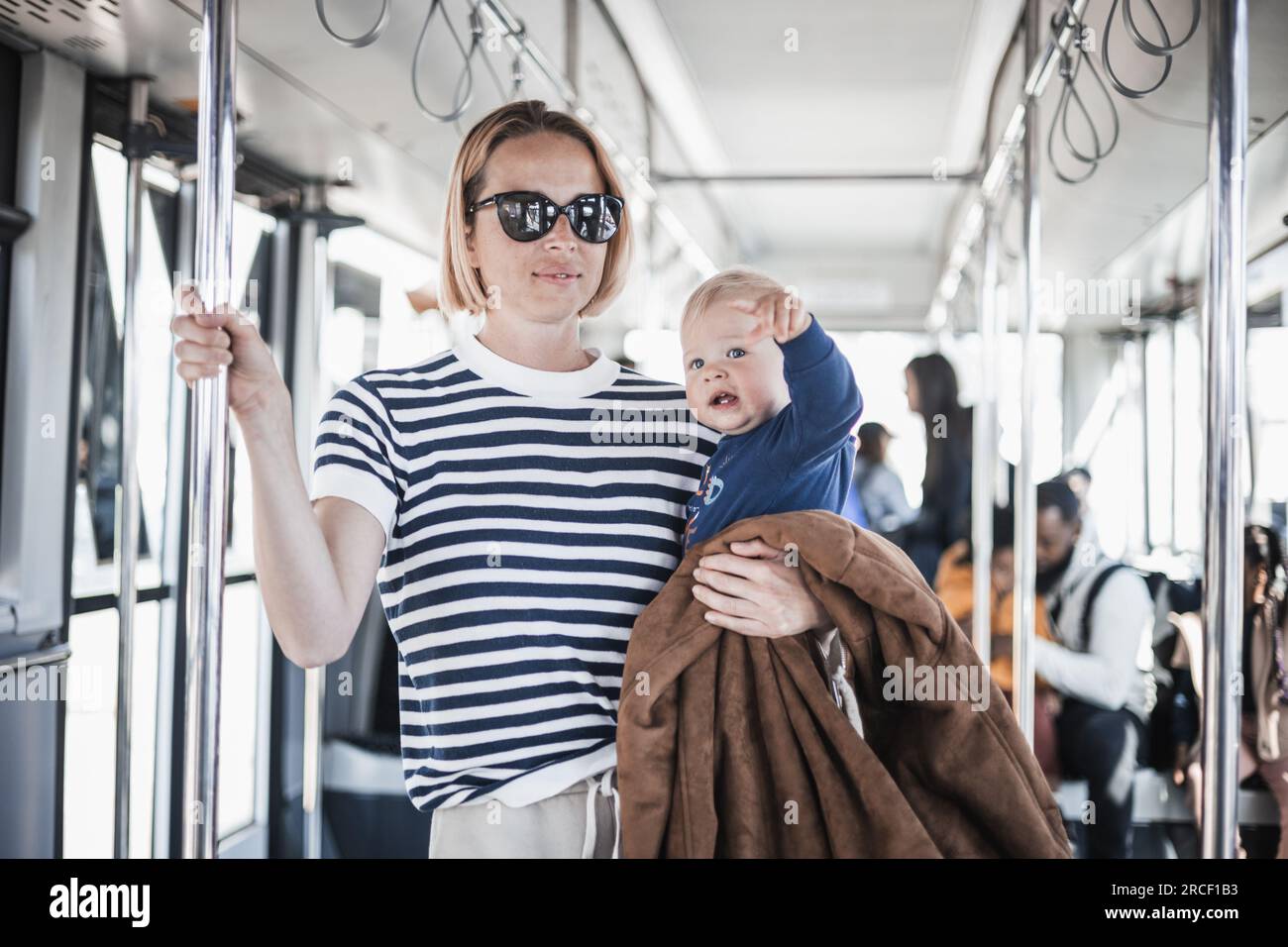 Young caucasian mother carries her child while standing and holding on ...