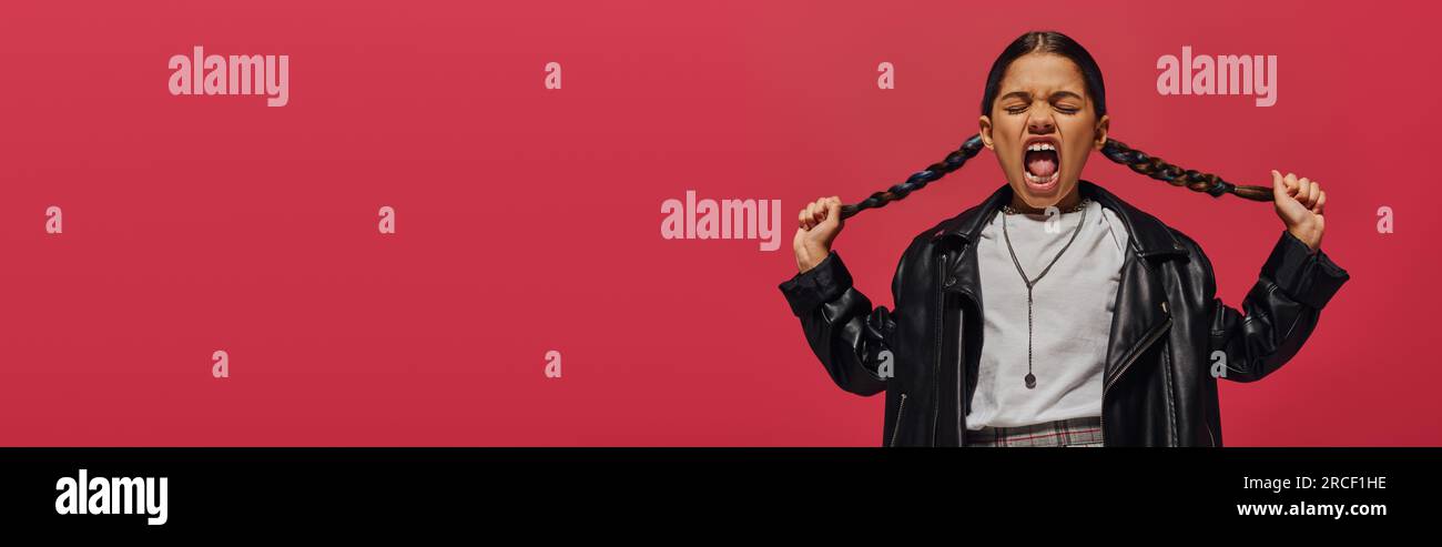 Mad and screaming preteen girl in fashionable leather jacket touching ...