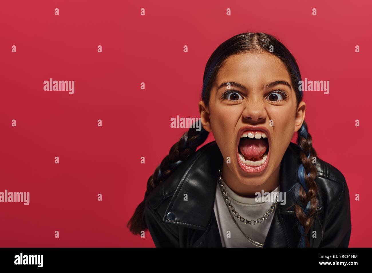 Portrait of mad preadolescent girl with hairstyle wearing leather ...