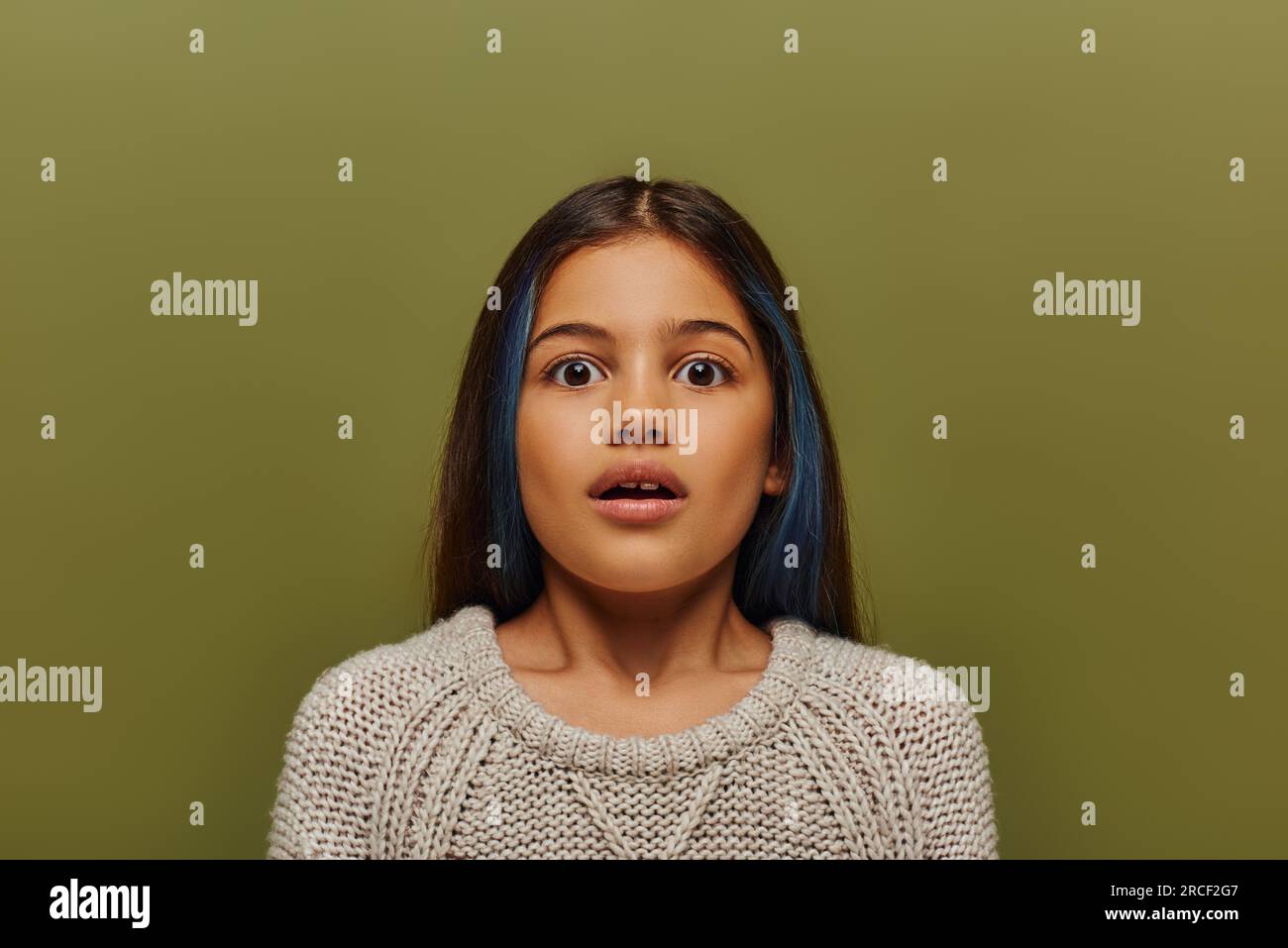 Portrait of scared and stylish preteen girl with dyed hair wearing ...