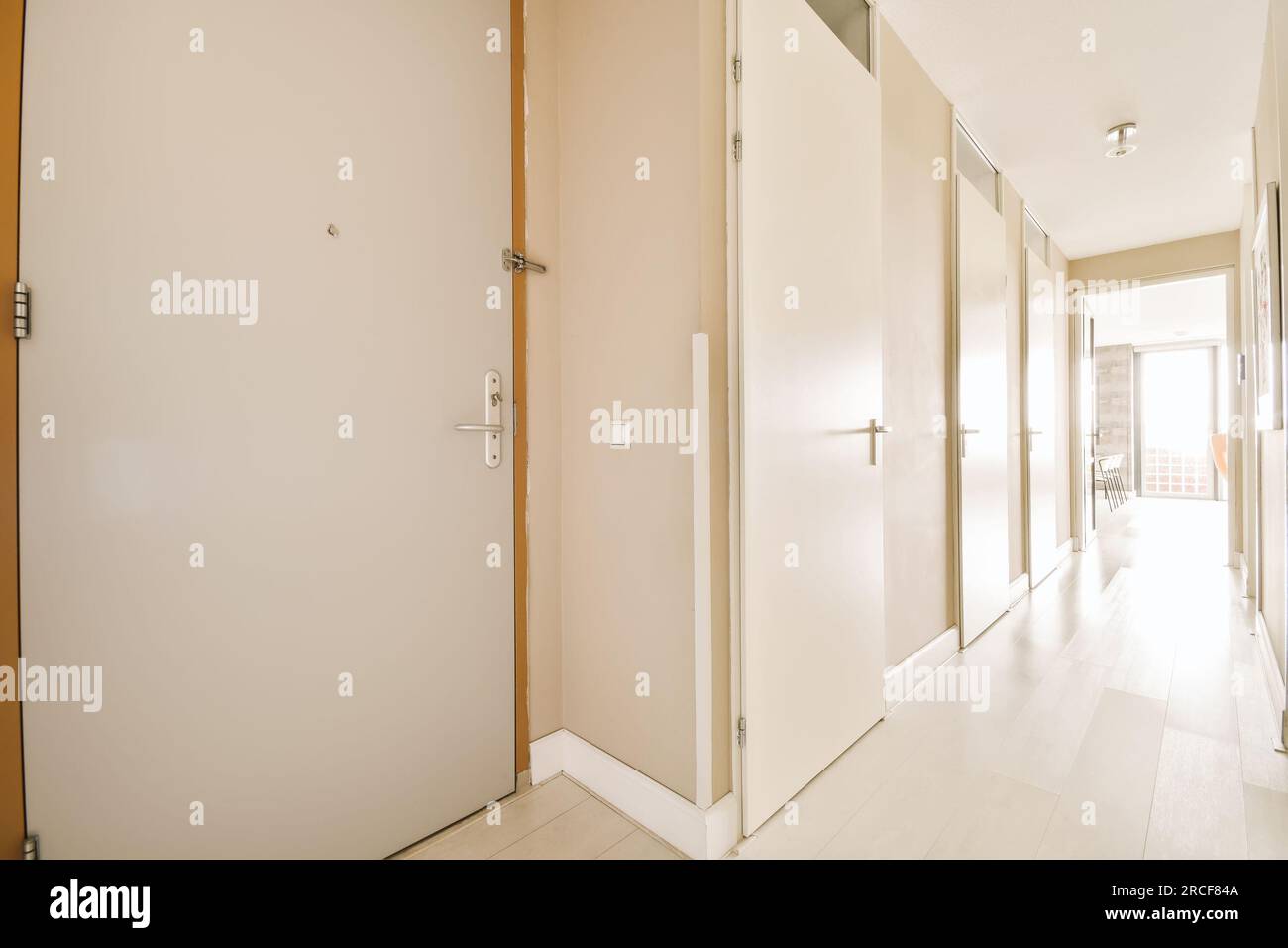 a long hallway with white walls and wood trim on the doors, which are ...