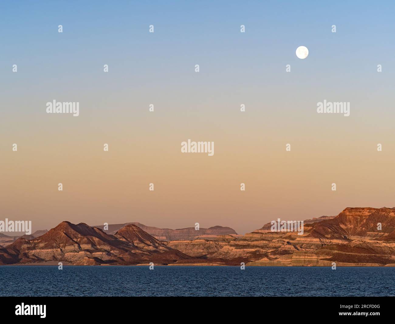A full moon setting over the Baja Peninsula across from Isla San Jose ...