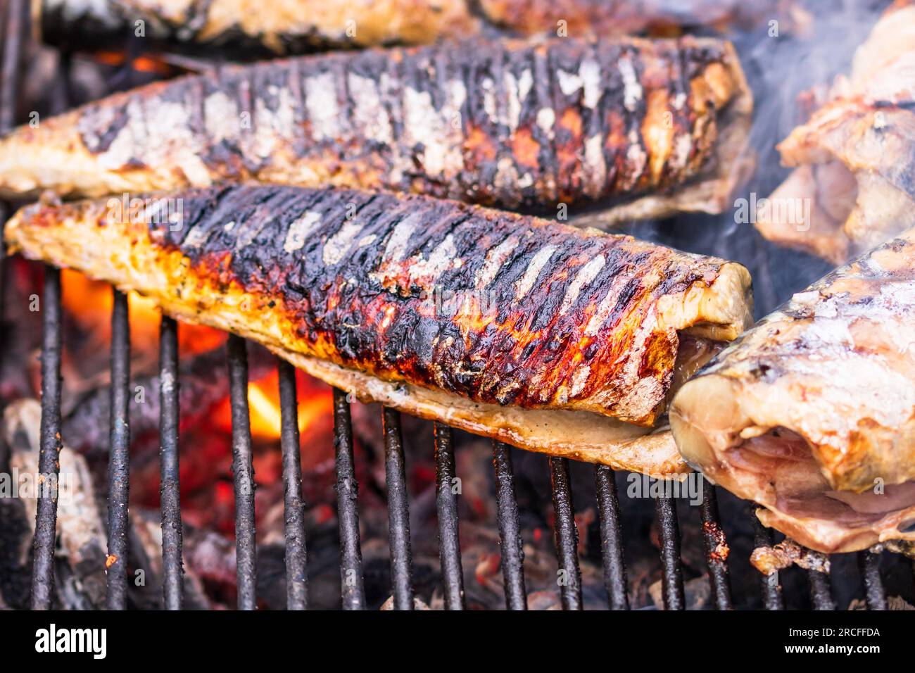 Grilled fish with smoke on a charcoal barbecue. Close up fish on the ...
