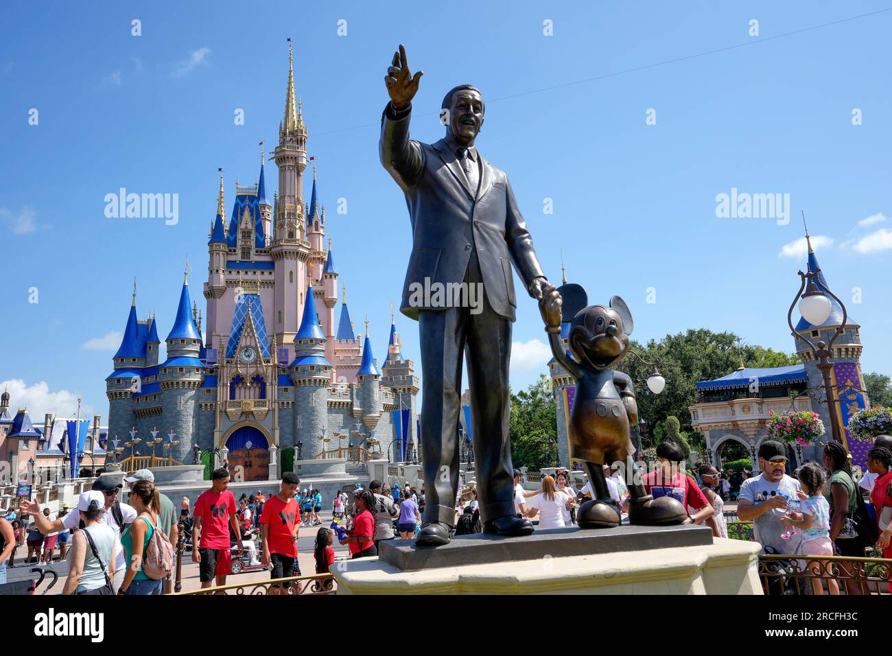 Park guests walk near the statue of Walt Disney and Mickey Mouse in the ...