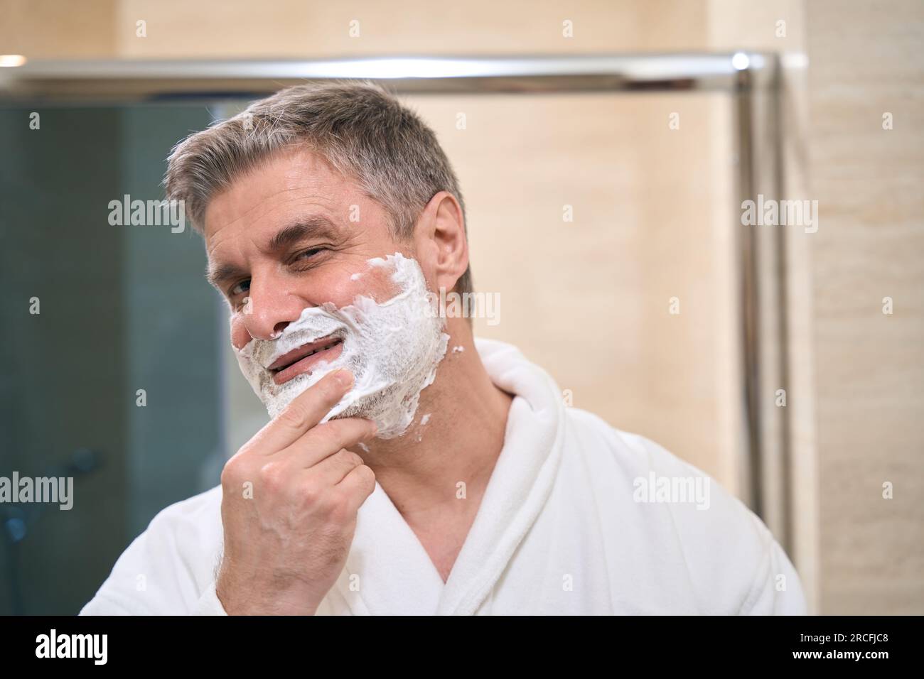 Adult male applying foam to face in the hotel Stock Photo - Alamy