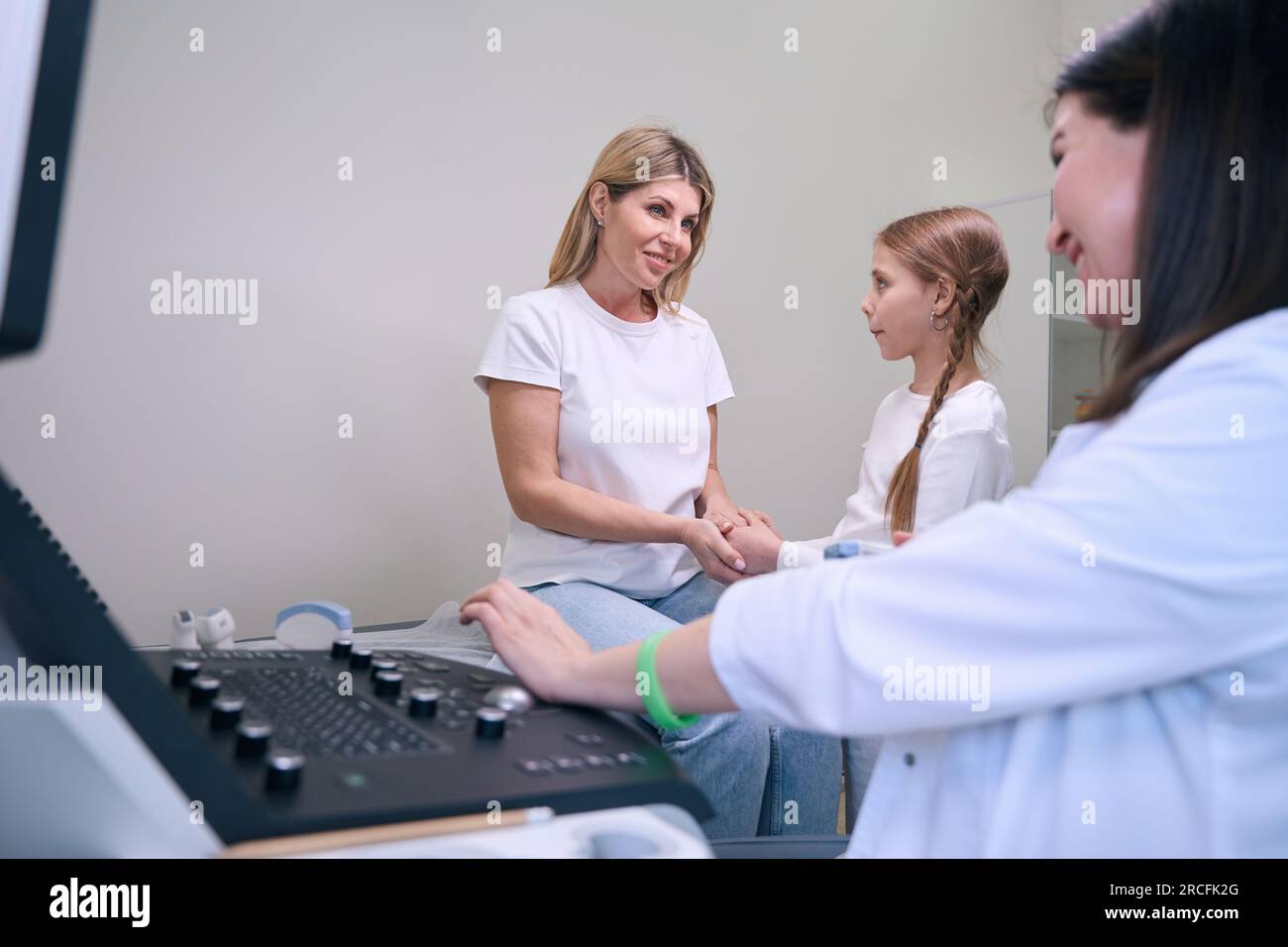 Young mother and daughter at a reception in ultrasound room Stock Photo ...