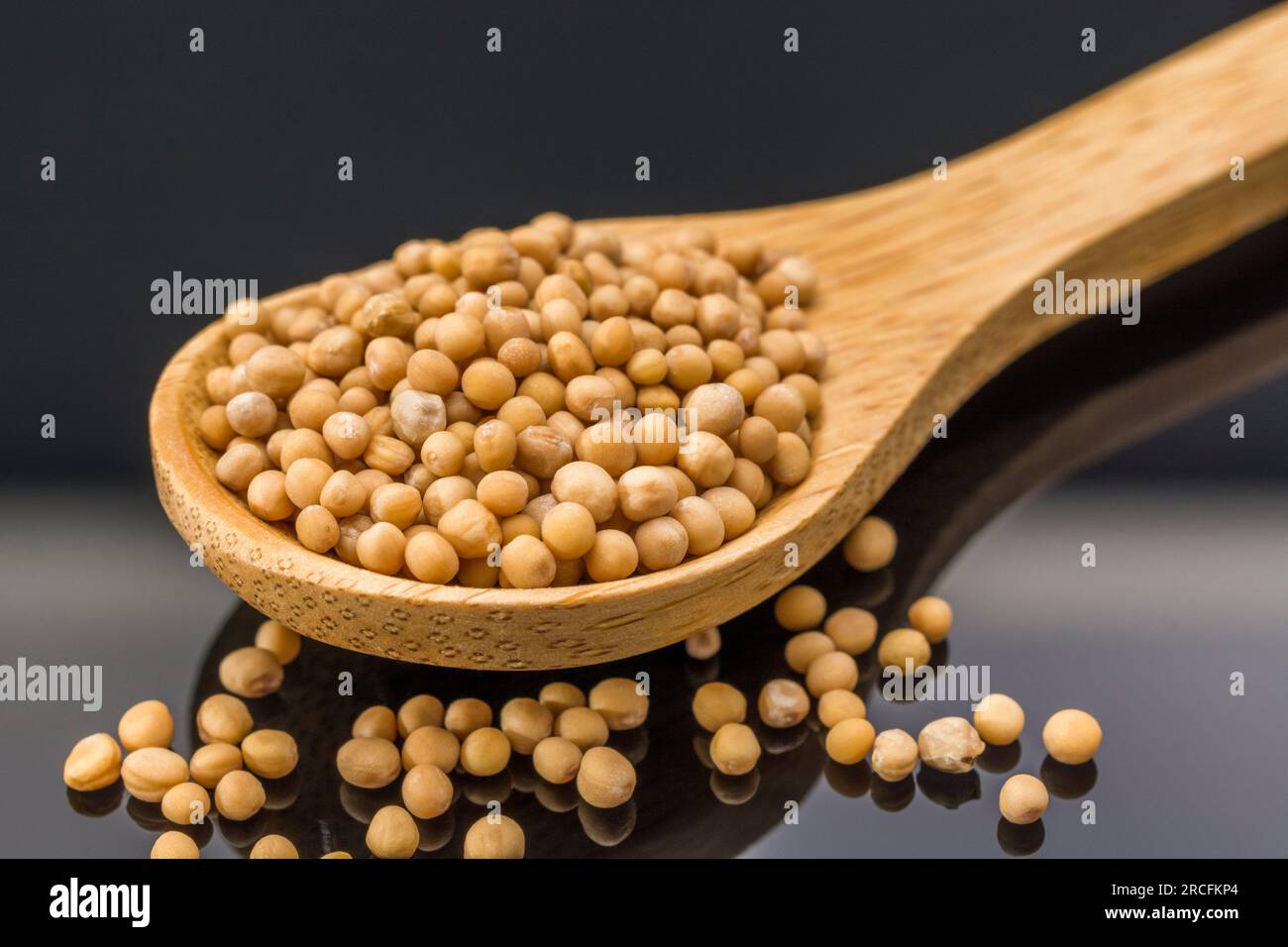 Seeds of White mustard / Sinapis alba on small bamboo spoon on ...