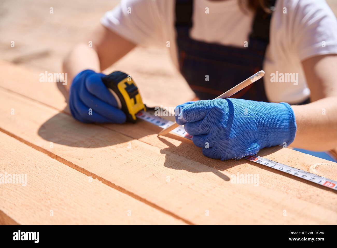 Carpenter measuring needed size with tape measure and making notes ...