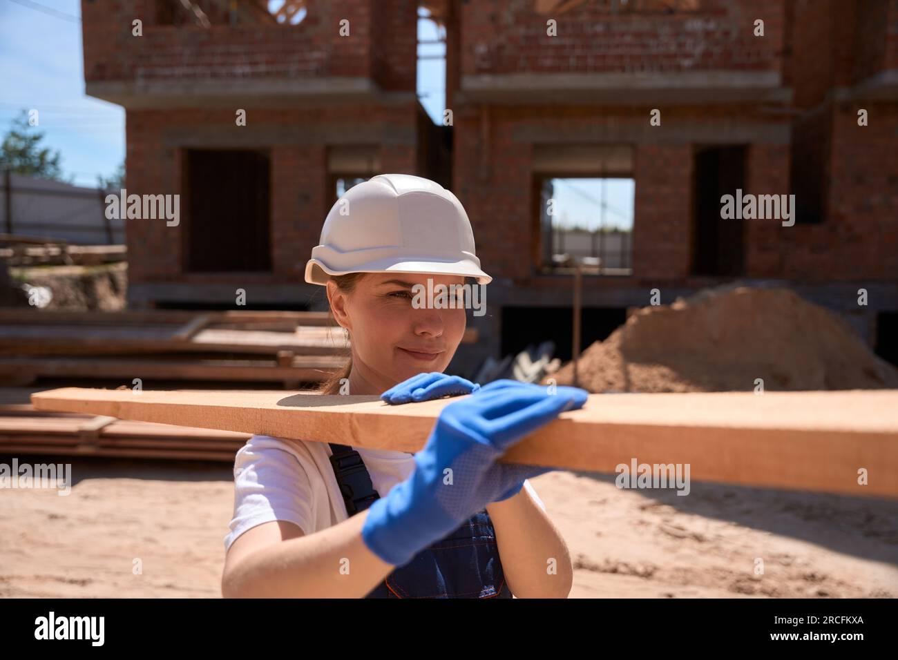 Woman building engineer bringing wooden girder, working at roof ...
