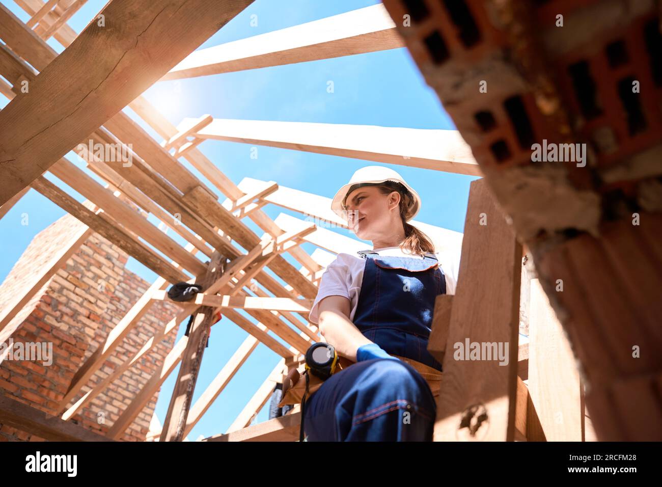Woman standing on ladder, checking readiness of wooden roof frame Stock ...