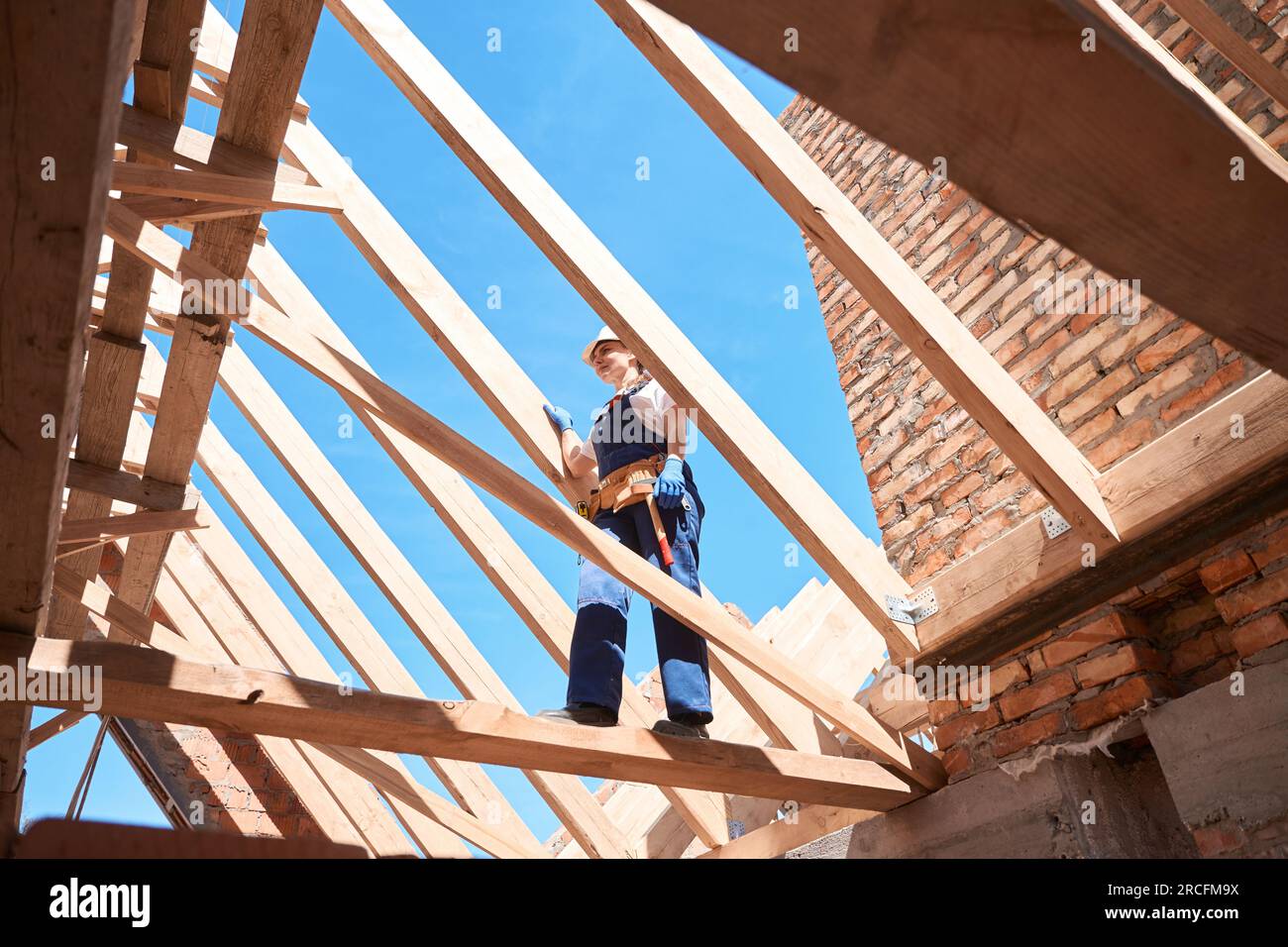 Woman lead architect climbing up on roof wooden construction to check ...