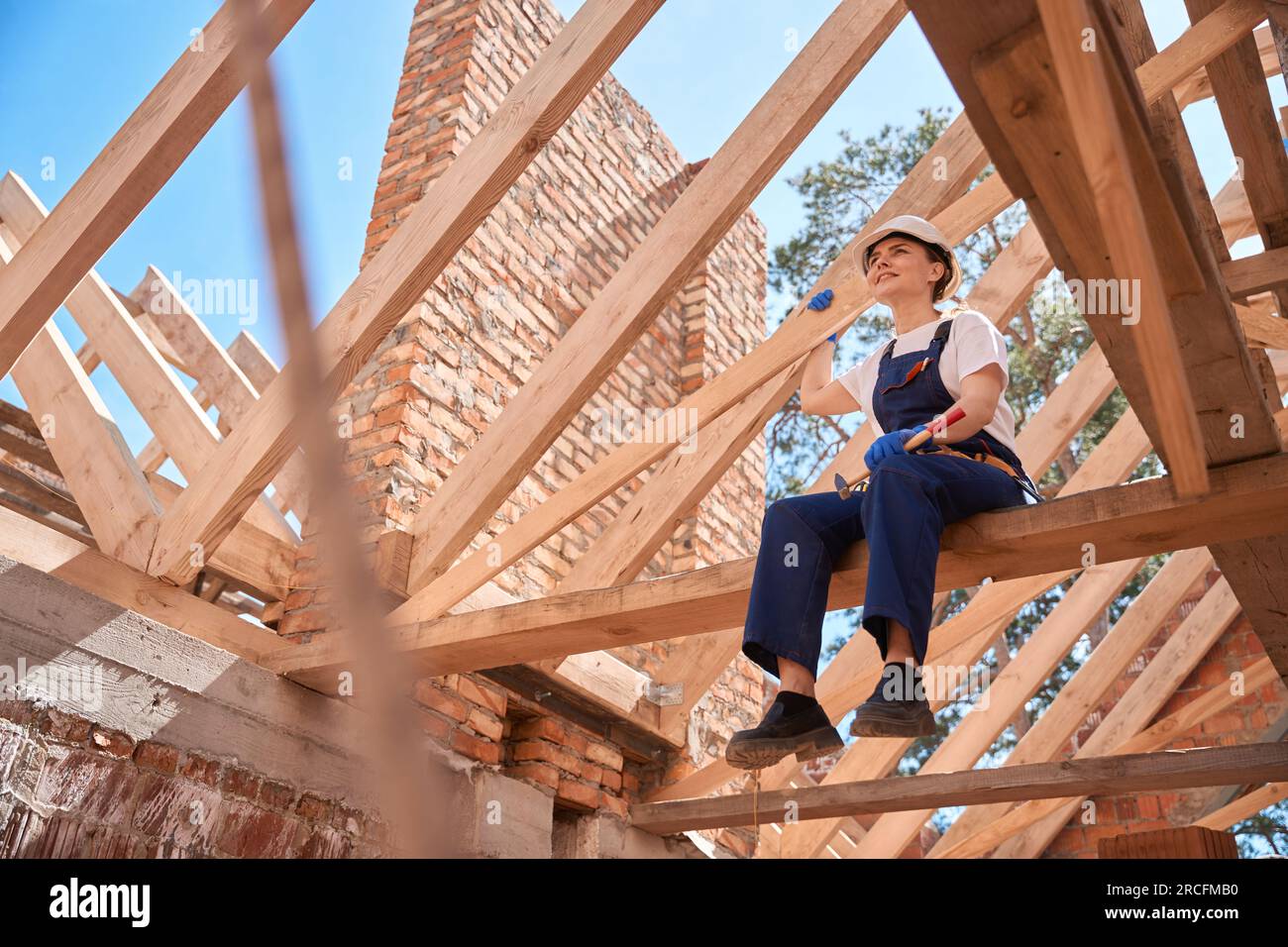 Woman roofer sitting on roof beam and enjoying done roofing works Stock ...