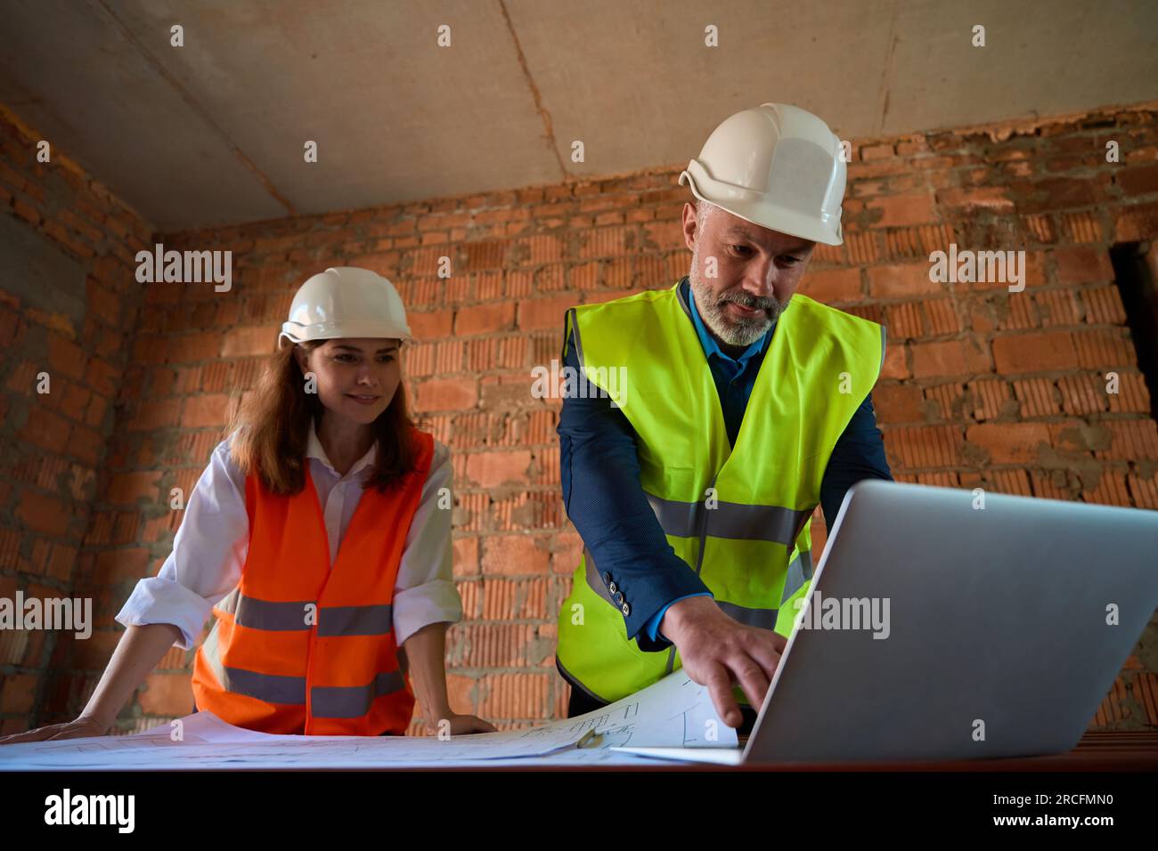 Builders entering measurements of building blueprint to make 3d layout ...