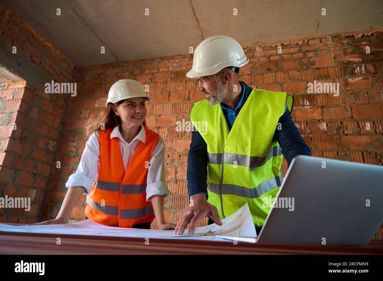 Building engineers examining paper blueprint and 3d layout Stock Photo ...