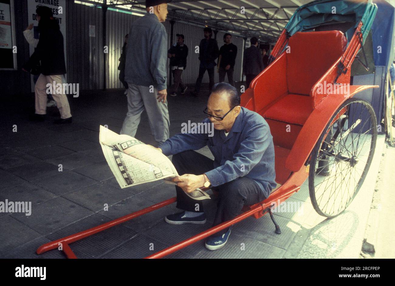A men reads the newspaper on his traditional Hand and walking Rickshaw ...