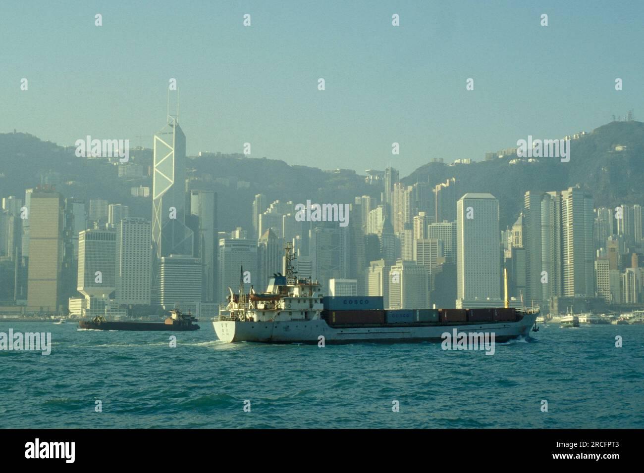 a cargo ship on the Victoria harbour in front of the Skyline of Central ...