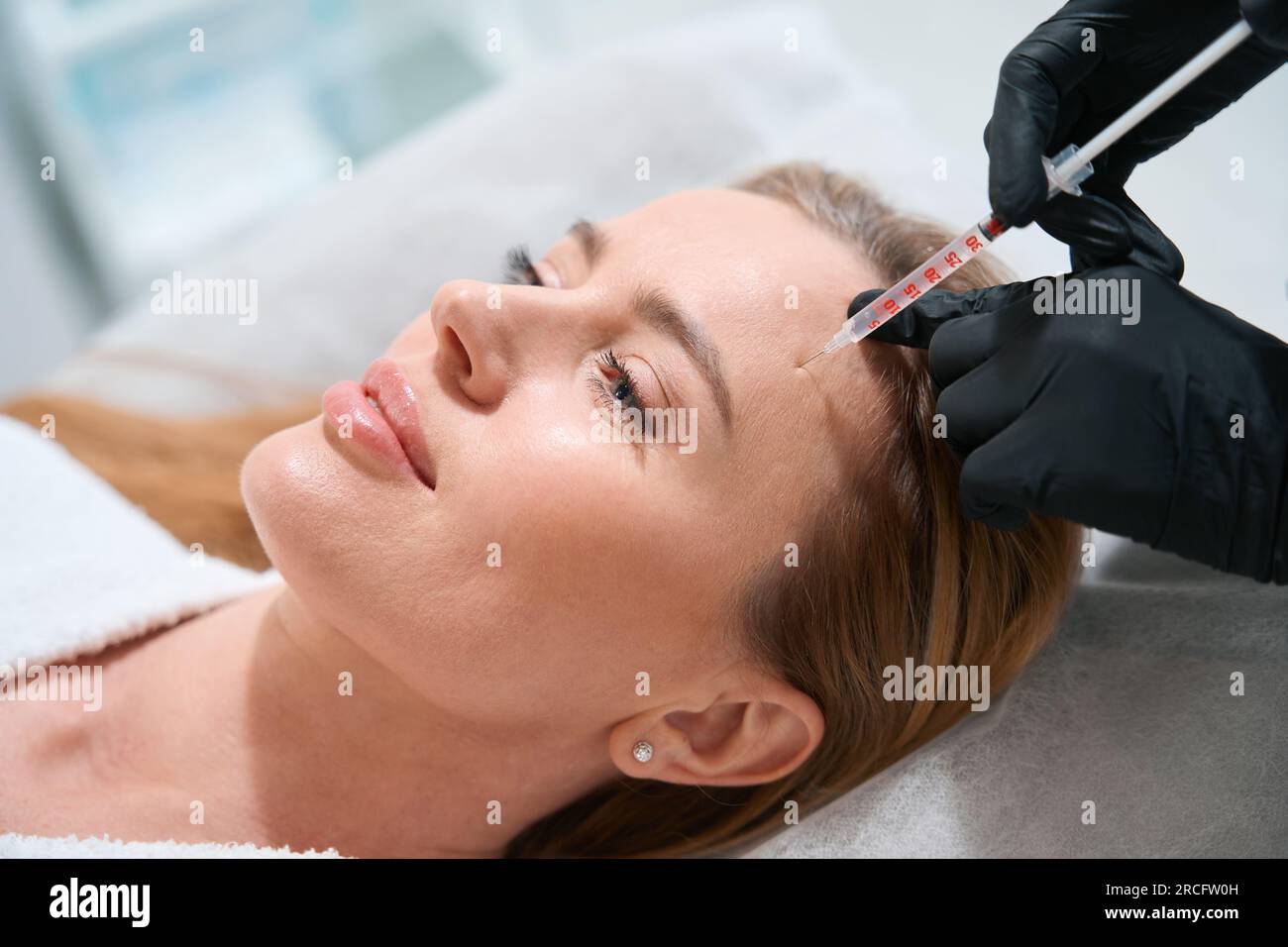 Beautiful female on an injection procedure in aesthetic medicine clinic ...