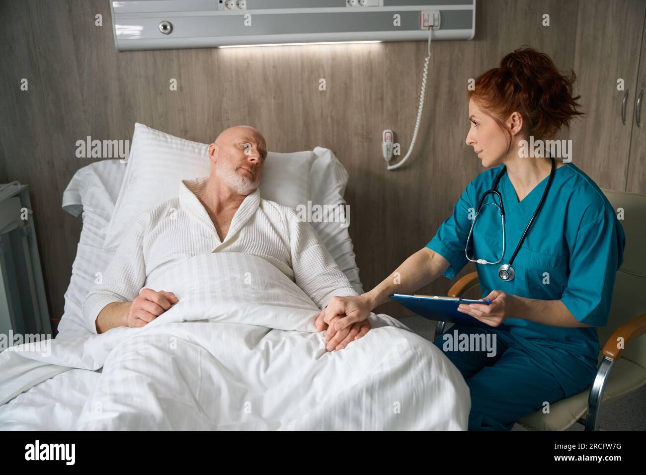 Beautiful medical practitioner encouraging her patient on bed in clinic ...