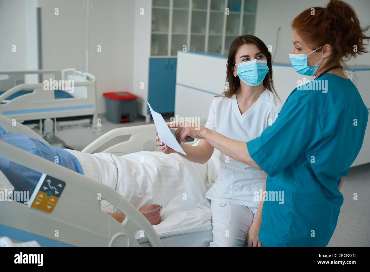 Female medical assistants discussing patient analysis at the hospital ...