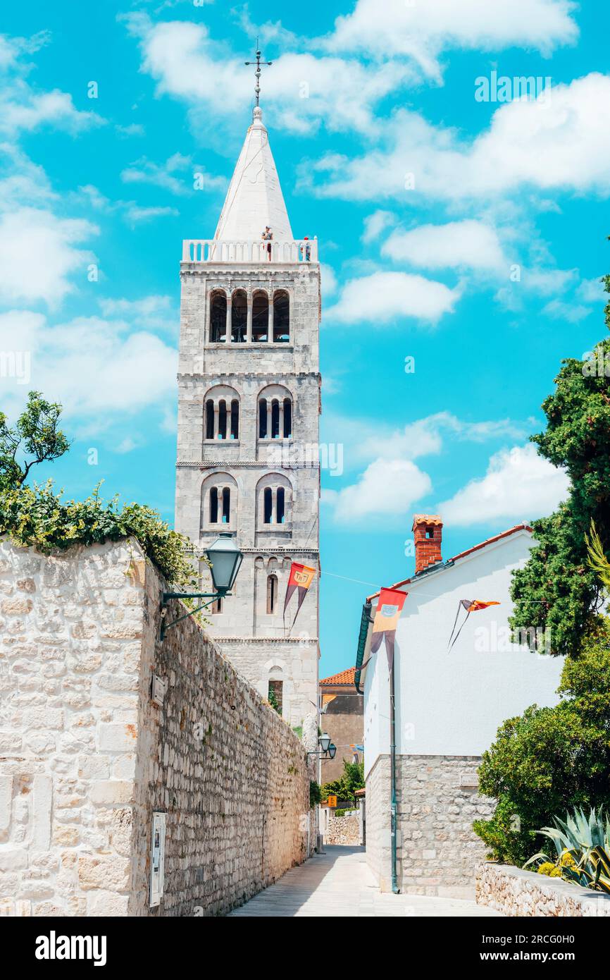 Bell tower of St. Mary's church against blue sky and narrow street of ...
