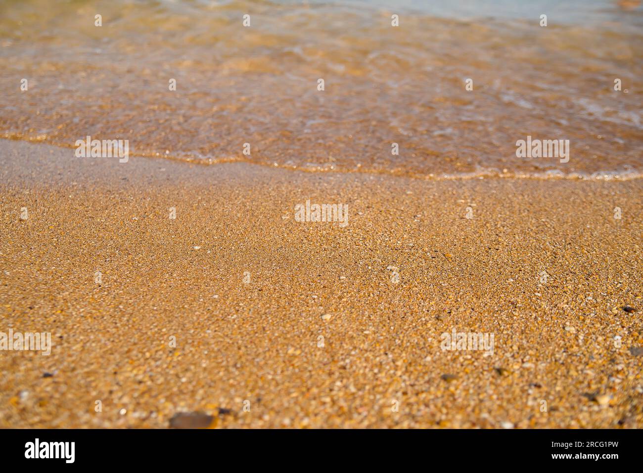 Golden sand at the beach, with soft touch of a calm waves of the ocean ...