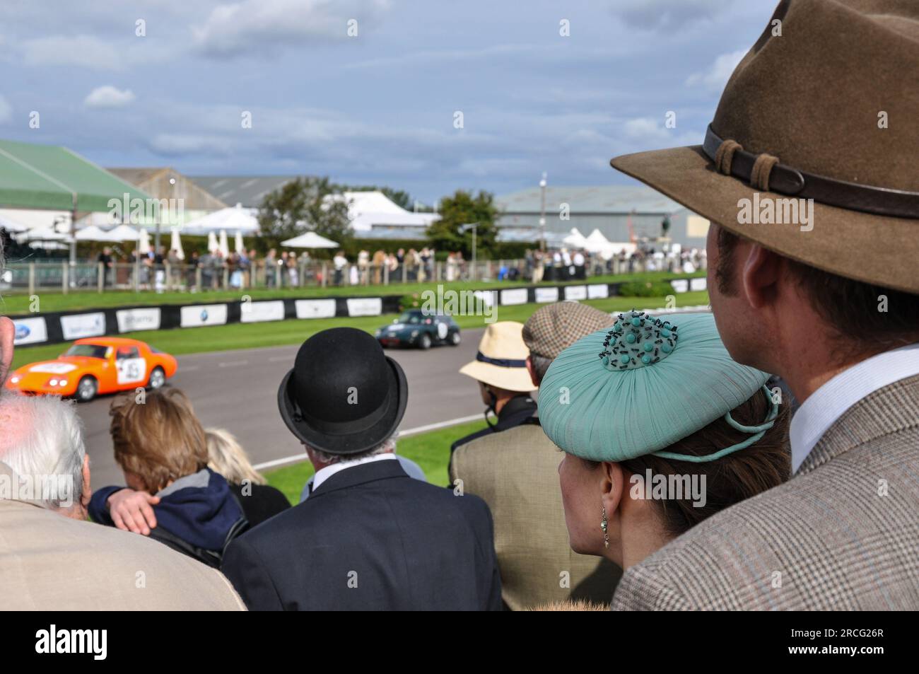 People in vintage clothing watching the vintage motor racing at the ...