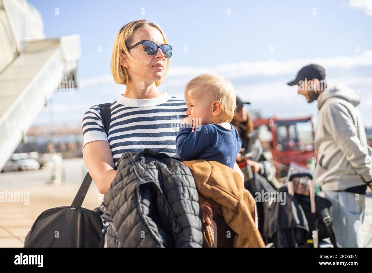 Motherat travelling with his infant baby boy child. Mom holding travel ...