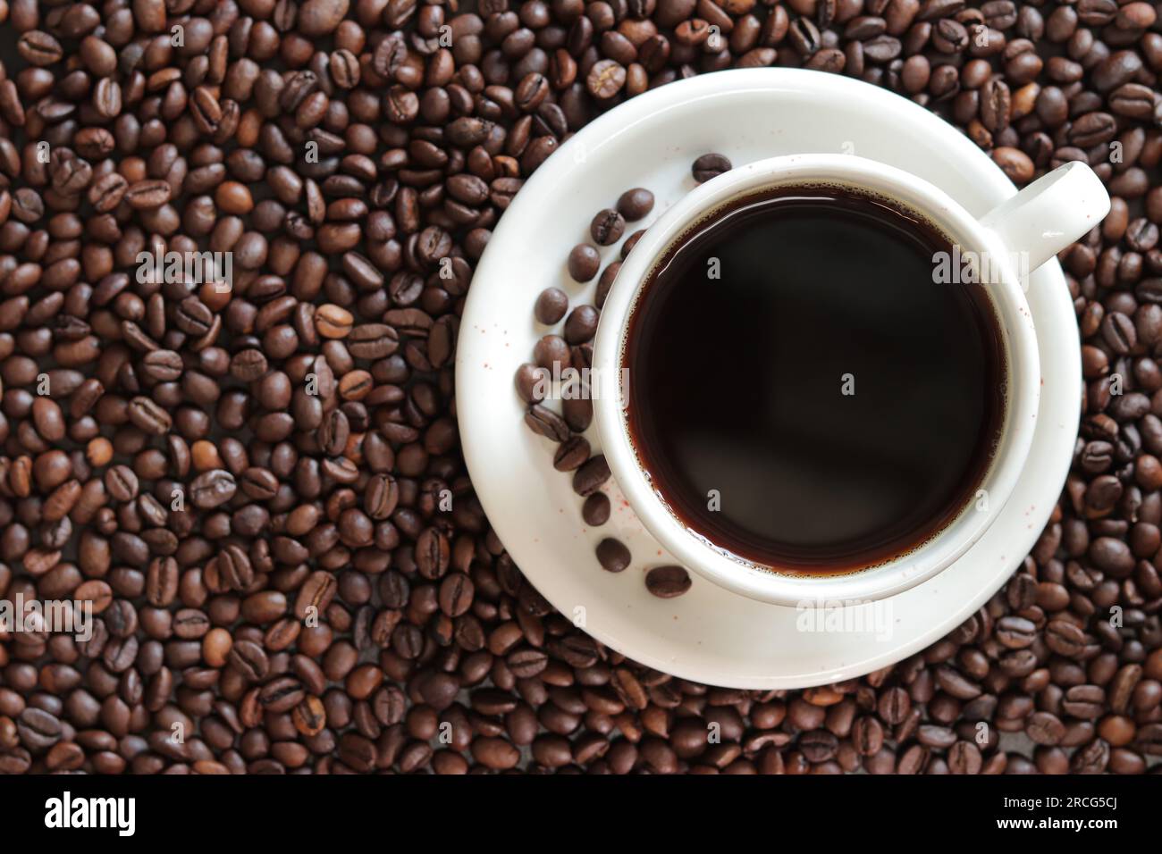 A cup of black coffee with scattered roasted coffee bean, top view ...