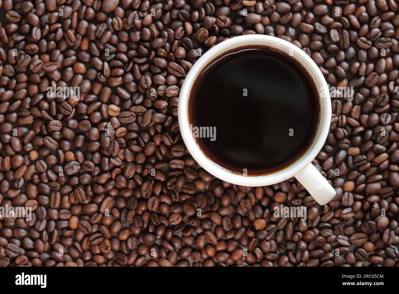A cup of black coffee with scattered roasted coffee bean, top view ...