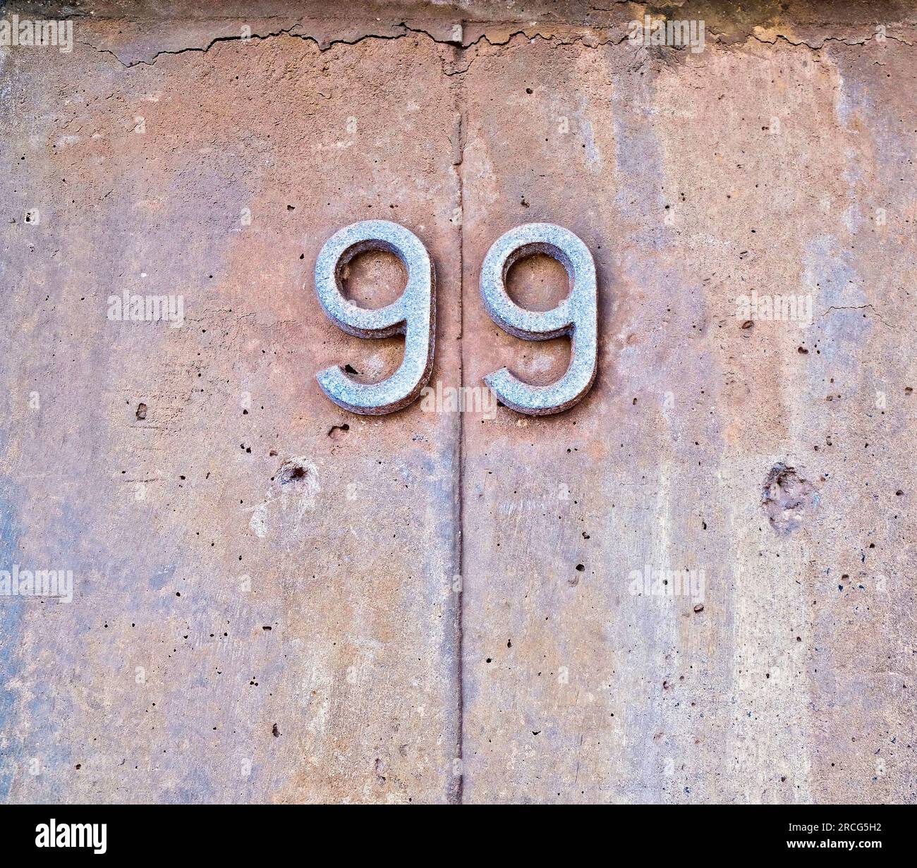 Number 99, ninety-nine, metallic digits on an opalescent concrete ...