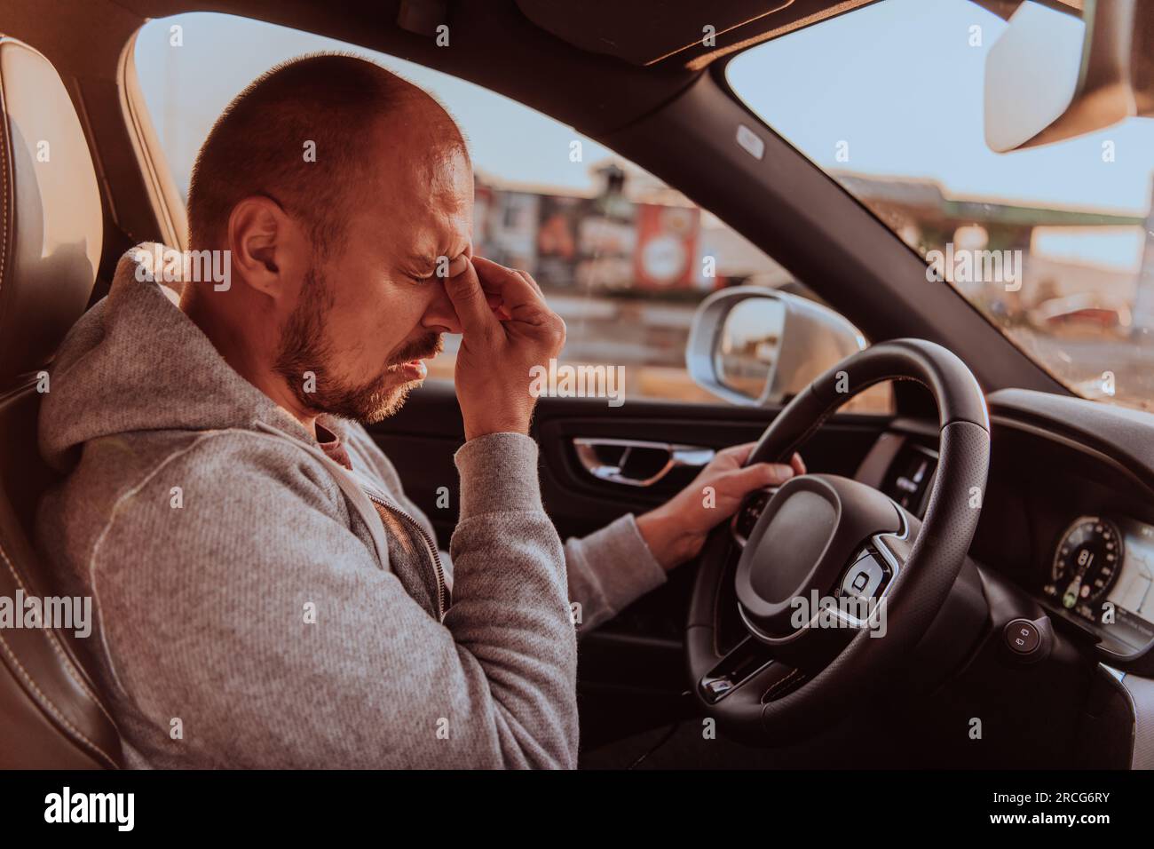 A tired driver holding his head. Exhausted and tired driver driving a ...