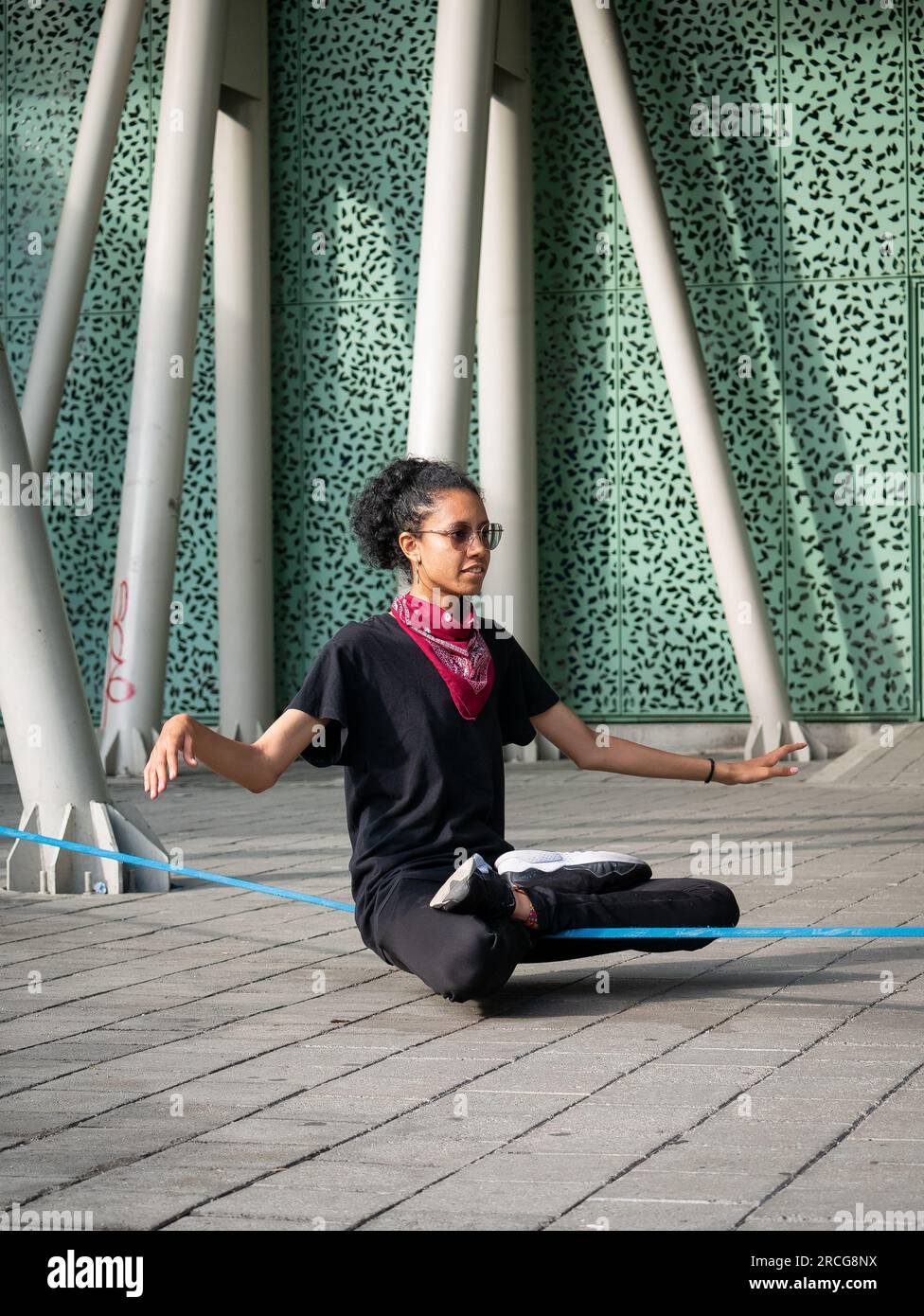 Colombian Woman Wearing Black Pants and a T-shirt is Sitting on a Blue ...